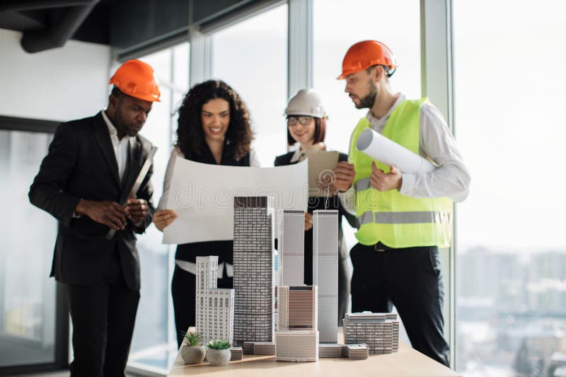 Multicultural Workers in Reflective Vest and Helmets with Blueprint ...