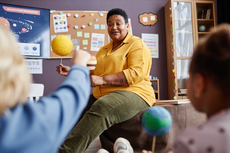 Focus on Mature Teacher with Planet of Sun Interacting with Schoolboy ...