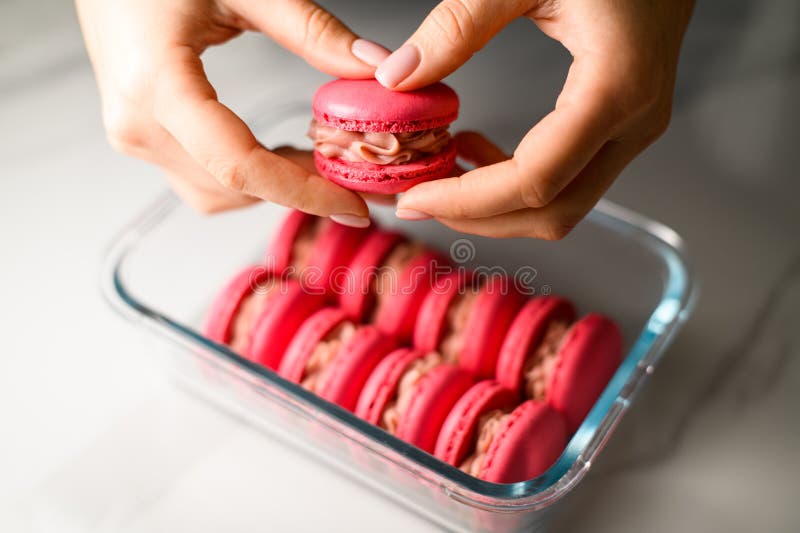 Focus on Red Macaroon in Female Hands Holding it Directly Above Other ...