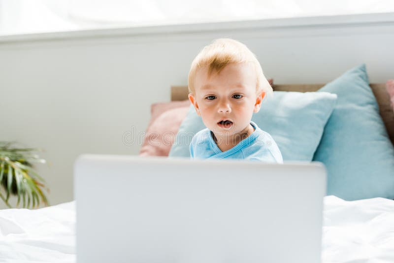 Focus of Surprised Toddler Kid Looking at Laptop in Modern Bedroom ...