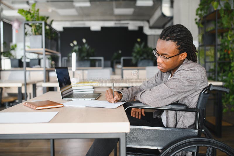 Focused African American Student in Wheelchair Writing Notes in Modern ...