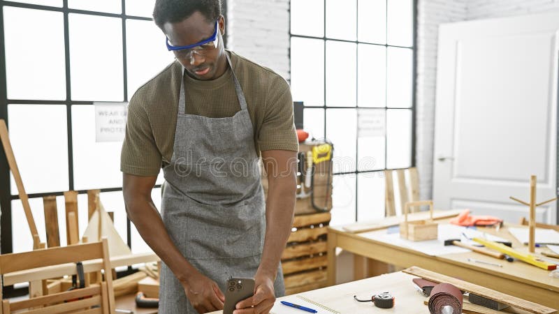 Focused African Man Using Smartphone in Sunlit Woodworking Workshop ...