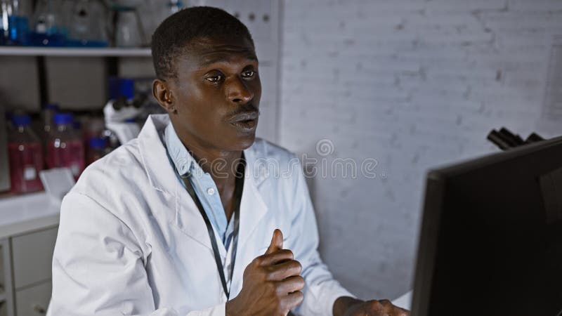 Focused African Man Wearing Lab Coat Working at Computer in a Modern ...