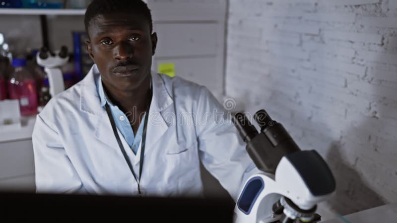 Focused African Scientist Analyzing Samples Using a Microscope in a ...