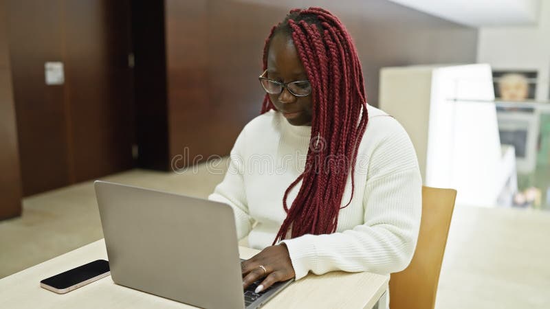 Focused African Woman with Braids Working on Laptop in Modern Office ... Focused African Woman with Braids Working on Laptop in Modern Office ...
