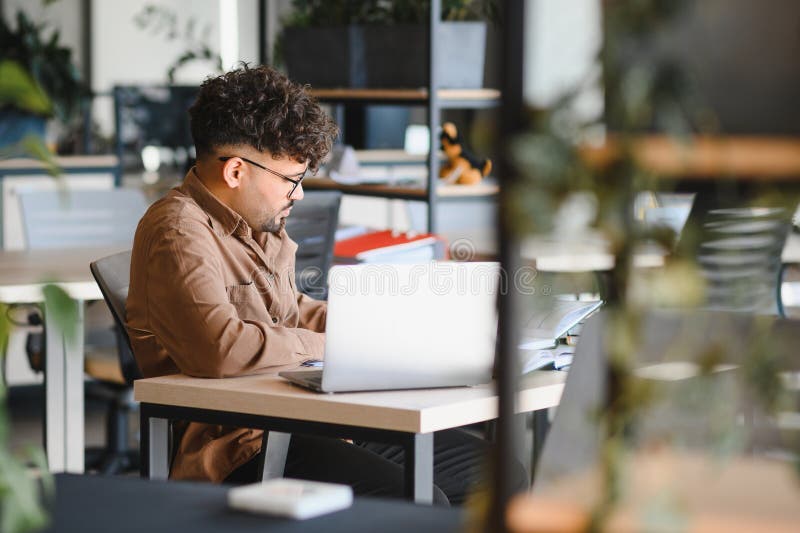 Focused Arab University Student Studying with Laptop in Modern Library ...