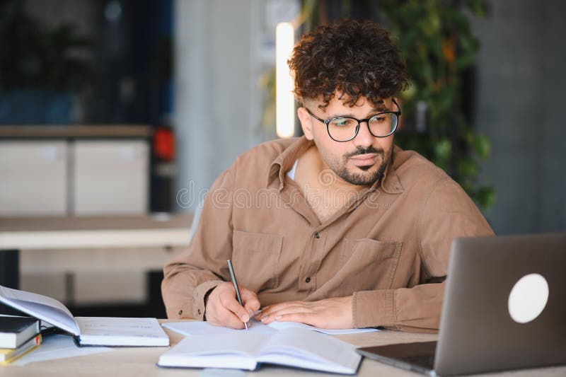 Focused Arab University Student Taking Notes while Studying Online with ...