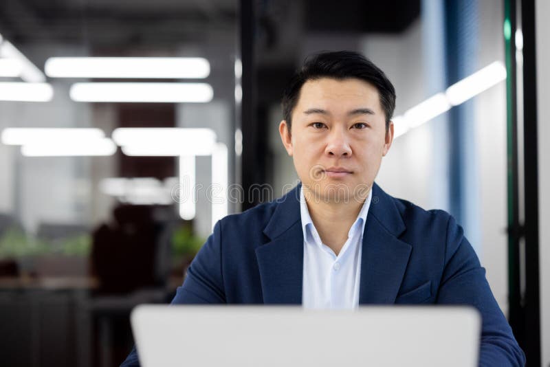 Confident Asian Businessman in a Blue Suit Working on Laptop at Modern ... Confident Asian Businessman in a Blue Suit Working on Laptop at Modern ...