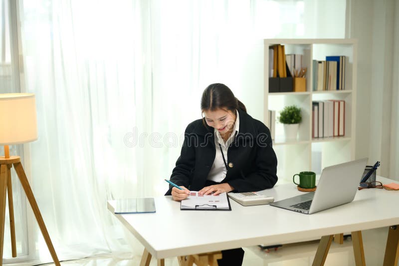Focused Asian Businesswoman Reviewing Documents and Using Laptop at ...