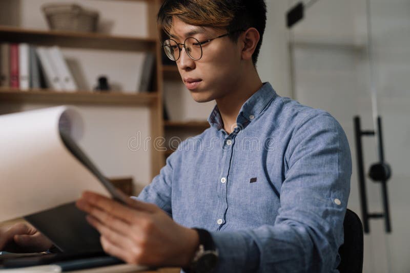 Focused Asian Guy Working with Papers while Sitting at Table Stock ...