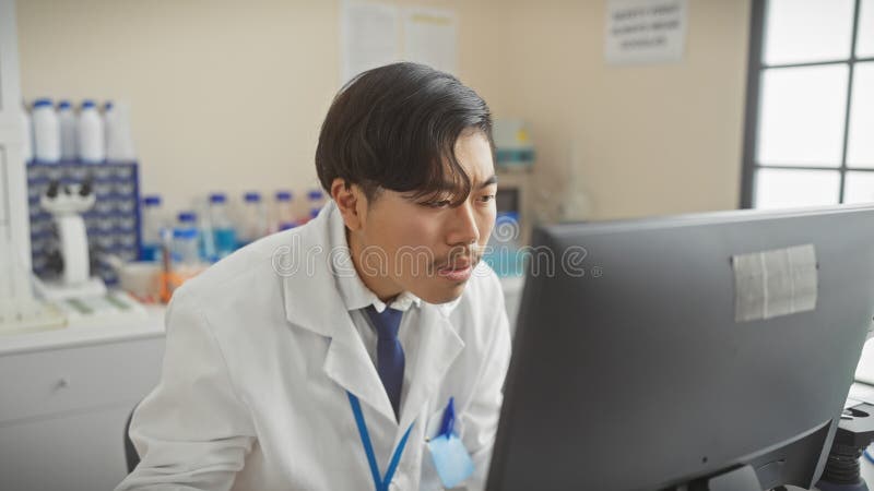 Focused Asian Man in Lab Coat Using Computer in a Medical Clinic Stock ...