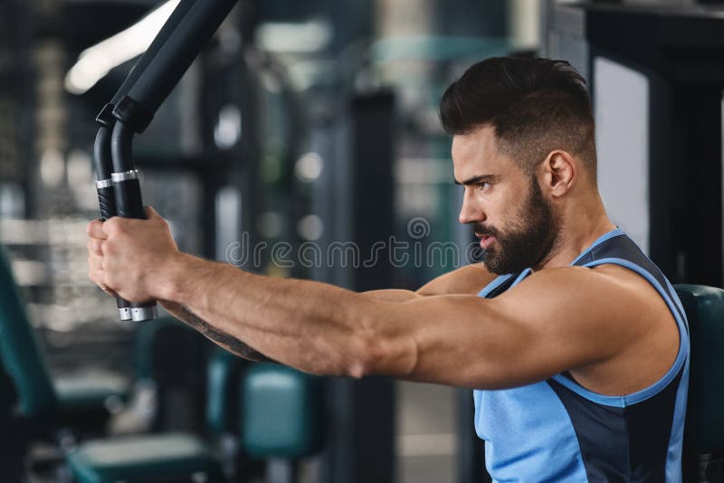 Focused Athlete Exercising on Training Machine at Gym Stock Image ...