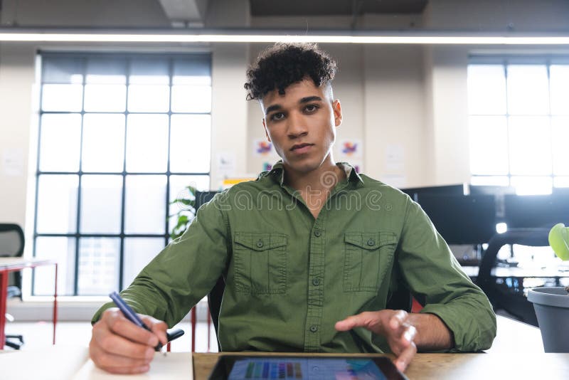 Focused Biracial Man Taking Notes during a Video Call at Office Stock ...