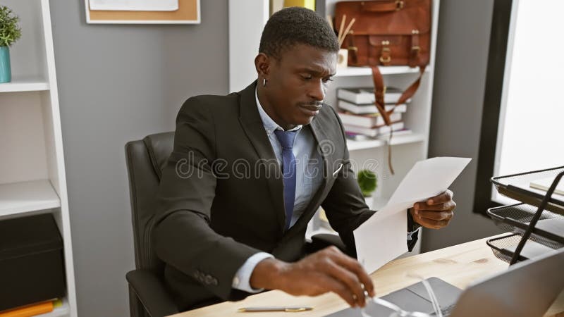 Focused Black Man Reading Documents in a Modern Office Setting ...