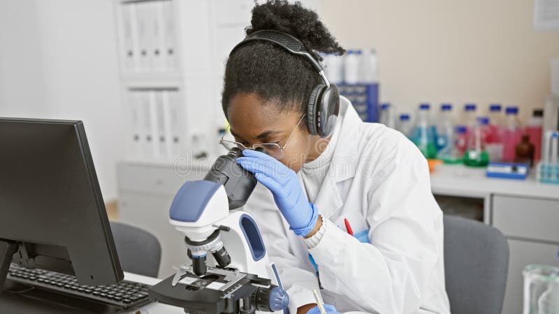 Focused Black Woman Scientist Analyzing Sample through Microscope in ...