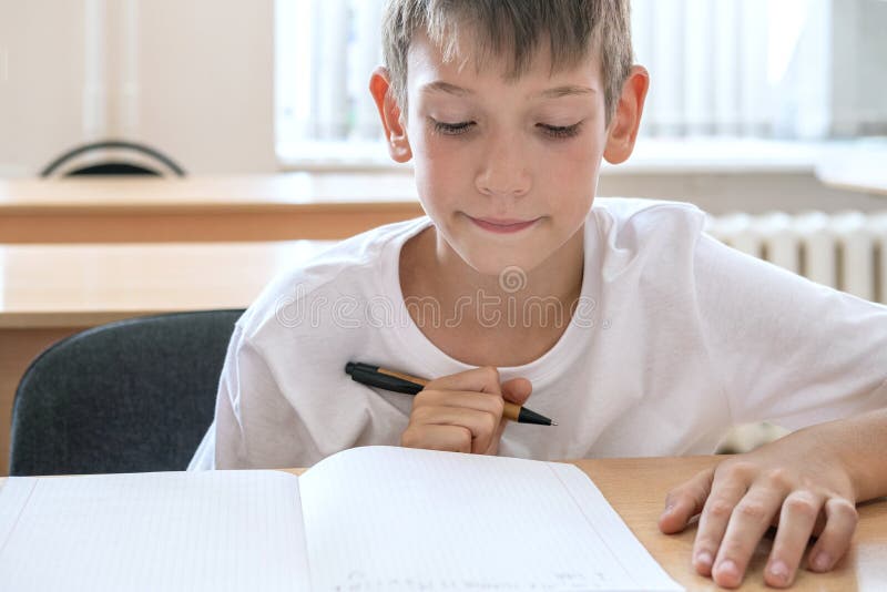 A Focused Boy Doing Homework, Writing Text in a Notebook at the Table ...
