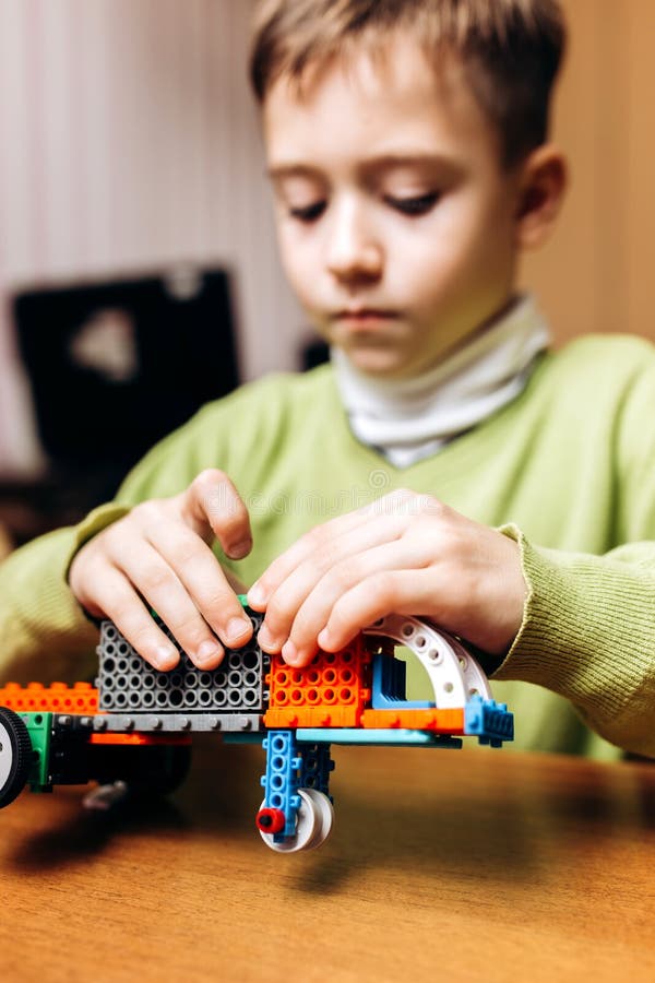 Focused Boy Dressed in Green Sweater Sits at the Table in the Robotics ...