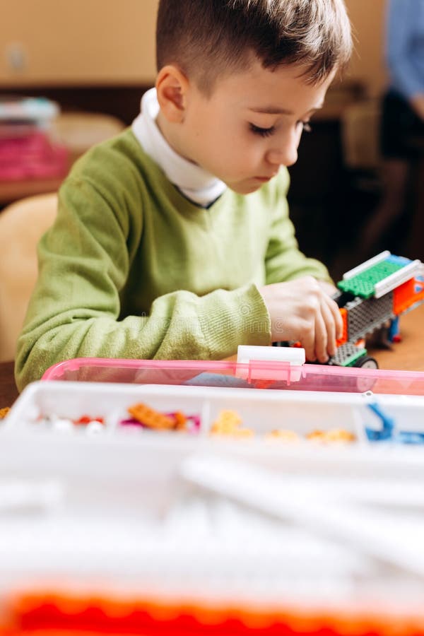 Focused Boy Dressed in Green Sweater Sits at the Table in the Robotics ...