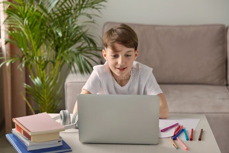 A Focused Boy Sits on the Couch and Does Homework at the Table. Stock ...