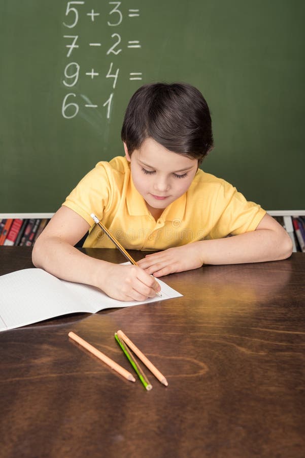 Focused Boy Writing in Copybook in Classroom Stock Photo - Image of ...