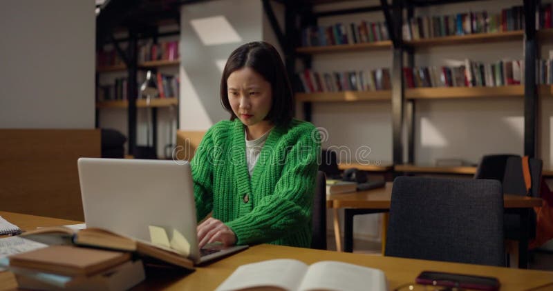 Focused Brunette Girl Working in Front of a Laptop and Taking Notes in ...