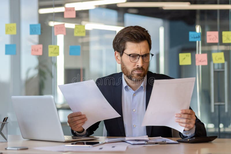 Focused Businessman Analyzing Documents in Modern Office Setting Stock ...