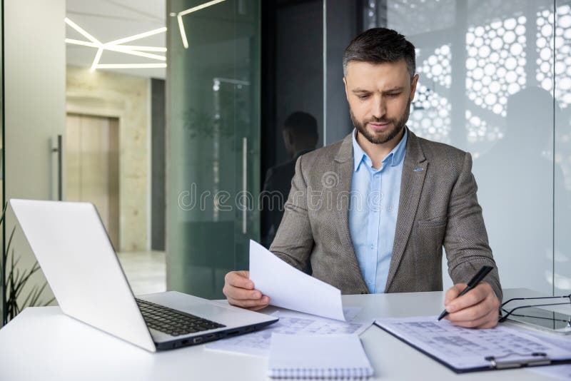 Professional Man Reviewing Documents at Modern Office Desk Stock Photo ...