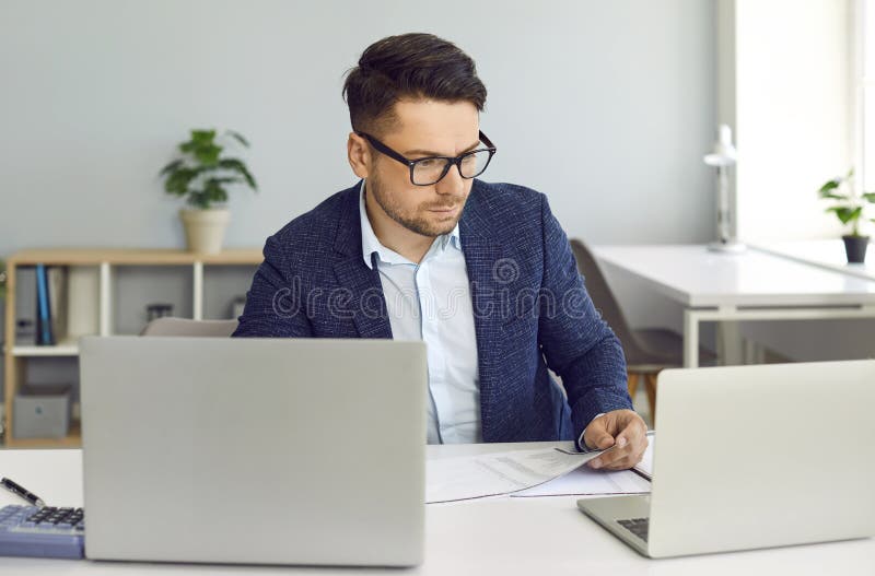 Focused Businessman Using Two Laptop Computers in Office Stock Photo ...