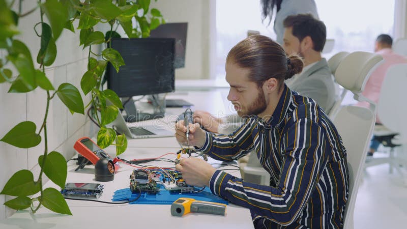 Male Caucasian Engineer in Lab Sitting by Desk Soldering Iron Circuit ...