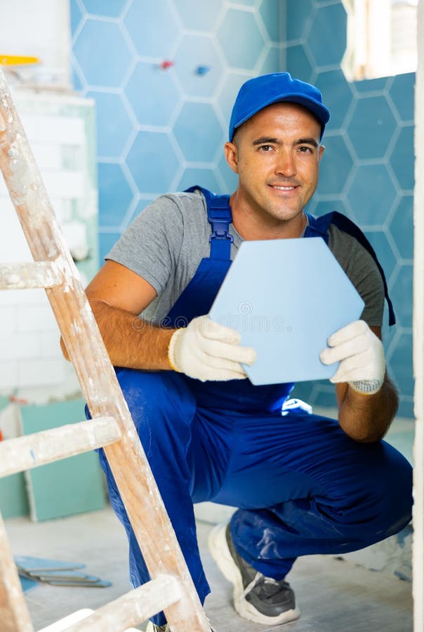 Focused Construction Worker in Work Clothes Sitting Squat Engaged in ...