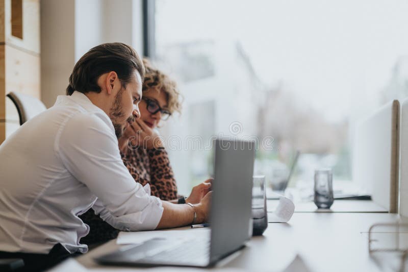 Two People Engage in a Focused Business Discussion Over a Laptop in a ...