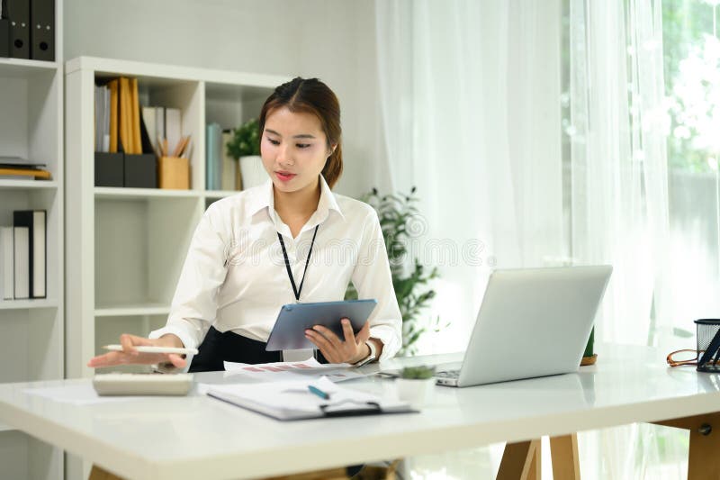 Focused Female Accountant Calculating Data and Using Digital Tablet in ...