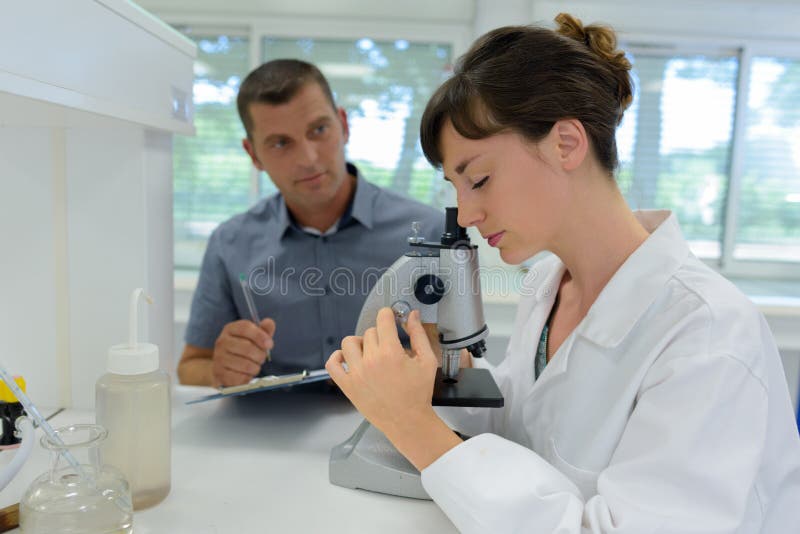 Focused Female Science Student Looking in Microscope in Laboratory ...