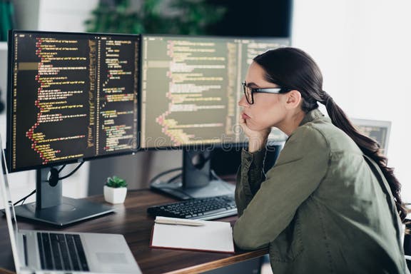 Focused Female Software Developer Analyzing Code on Multiple Monitors in Modern Home Office ...