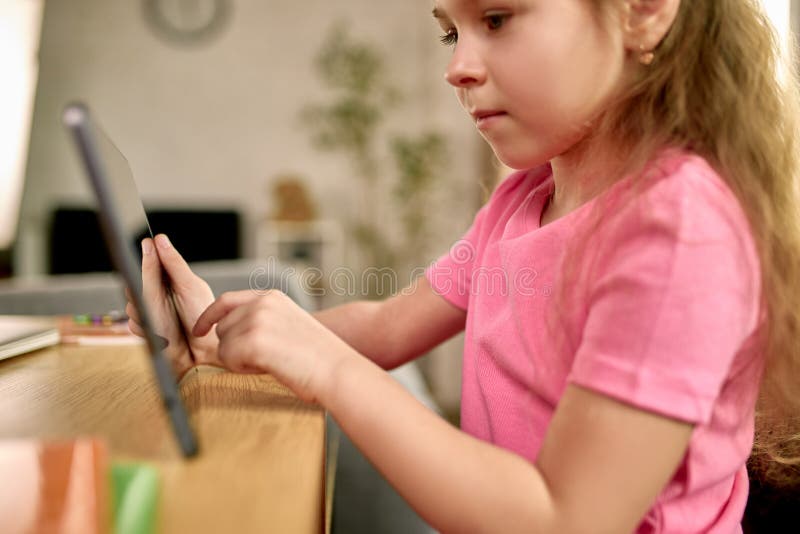 Focused Girl in Pink Shirt Interacting with Tablet during Remote ...