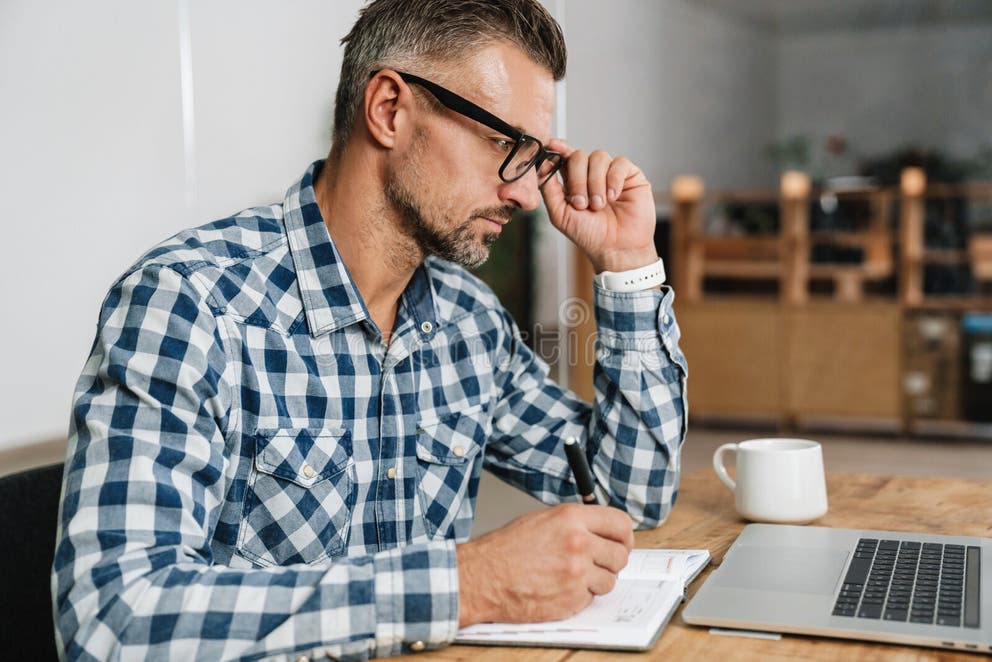 Focused Grey Man Writing Down Notes while Working with Laptop Stock ...
