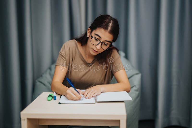 Focused High School Student Writing Notes at a Desk in Classroom Stock ...