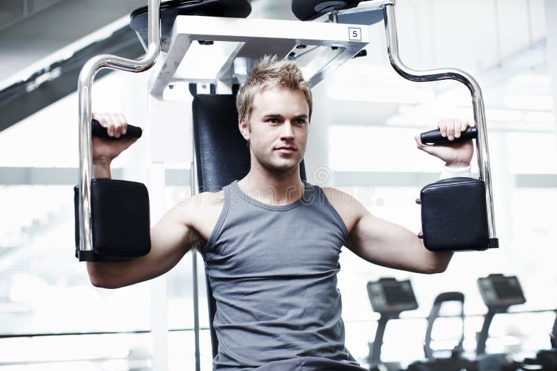 Focused on His Workout. a Handsome Young Man Using an Exercise Machine ...
