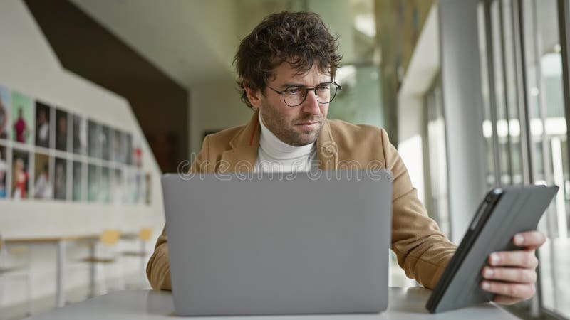 A Focused Hispanic Man with a Beard Working on a Laptop in a Modern ...