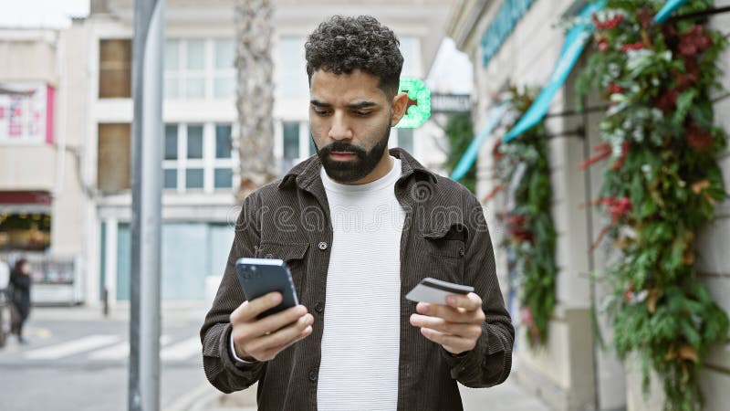 Focused Hispanic Man Using Smartphone while Holding Credit Card ...