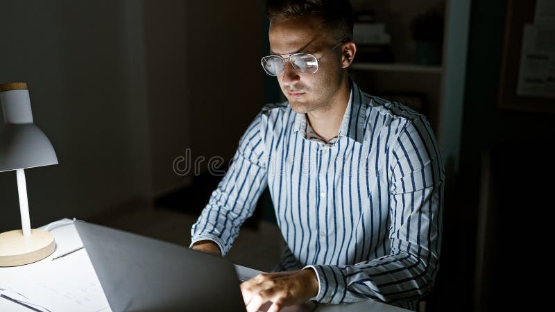 A Focused Hispanic Man at Work Late in an Office, Illuminated by the ...