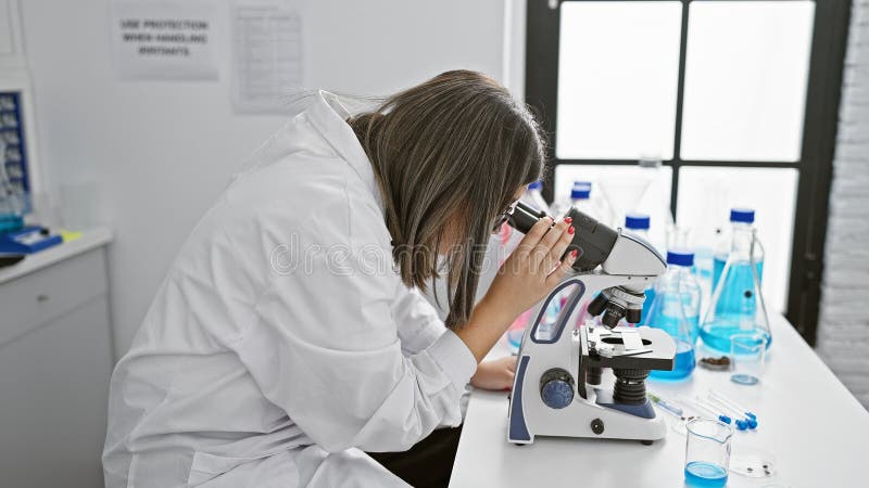 A Focused Hispanic Woman Scientist Using a Microscope in a Modern ... A Focused Hispanic Woman Scientist Using a Microscope in a Modern ...