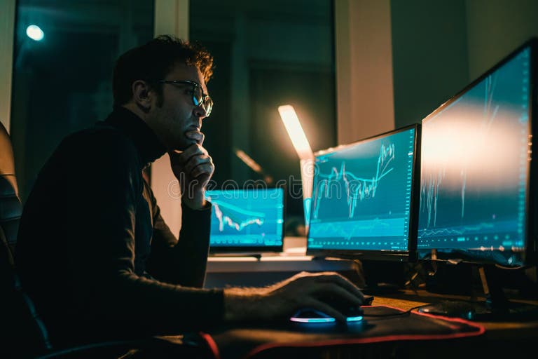 Focused Individual Analyzing Data Trends in a Dimly Lit Workspace at ...