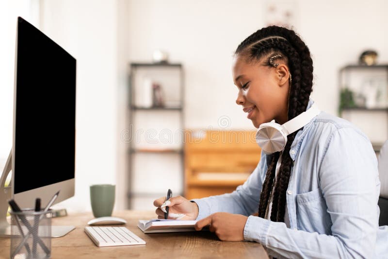 Focused Lady Student with Headphones Taking Notes from Computer Stock ...
