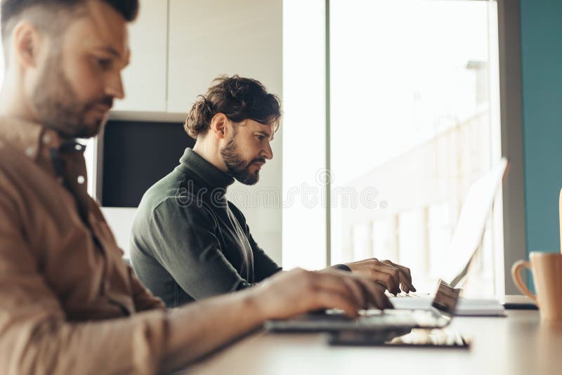 Focused Male Colleagues Working on Laptop Computers at Modern Office ...
