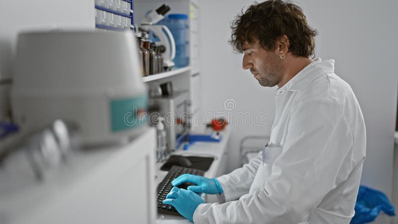 A Focused Man in Lab Coat Typing on a Computer in a Modern Laboratory ...