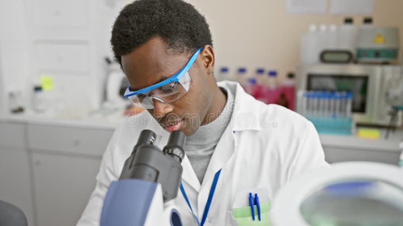 A Focused Man in Lab Coat Using a Microscope in a Modern Laboratory ...