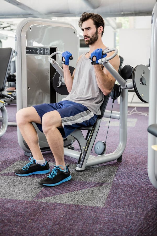 Focused Man Using Weights Machine for Arms Stock Photo - Image of ...