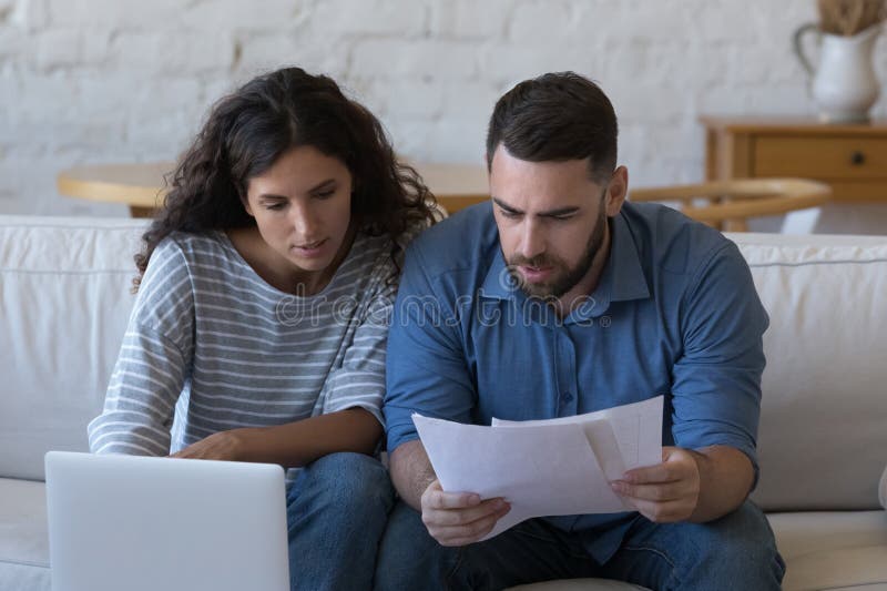 Focused Married Couple Reading Paper Documents at Laptop Stock Photo ...
