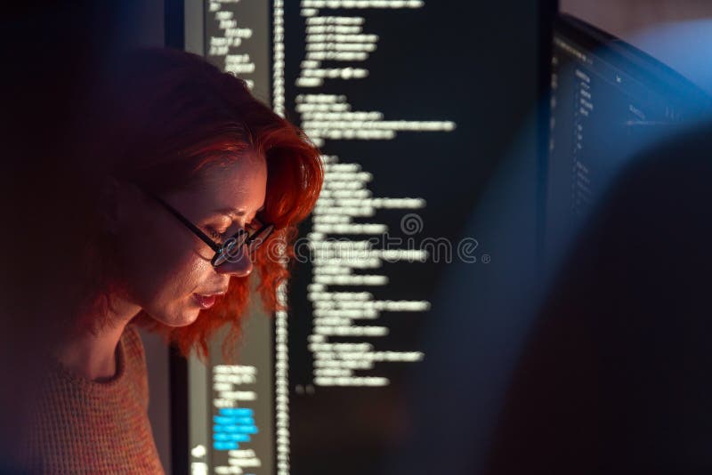 Focused Programmer and Software Developer Works in Dark Workspace, Screen Glowing with Code ...